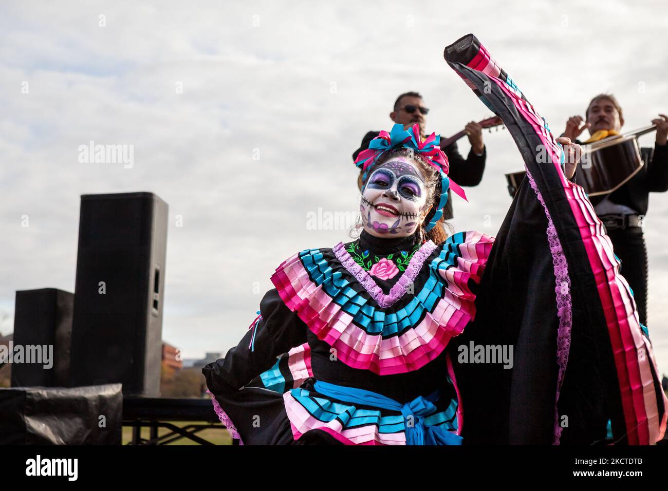 A woman dressed as a Catrina dances to the music of a mariachi band ...