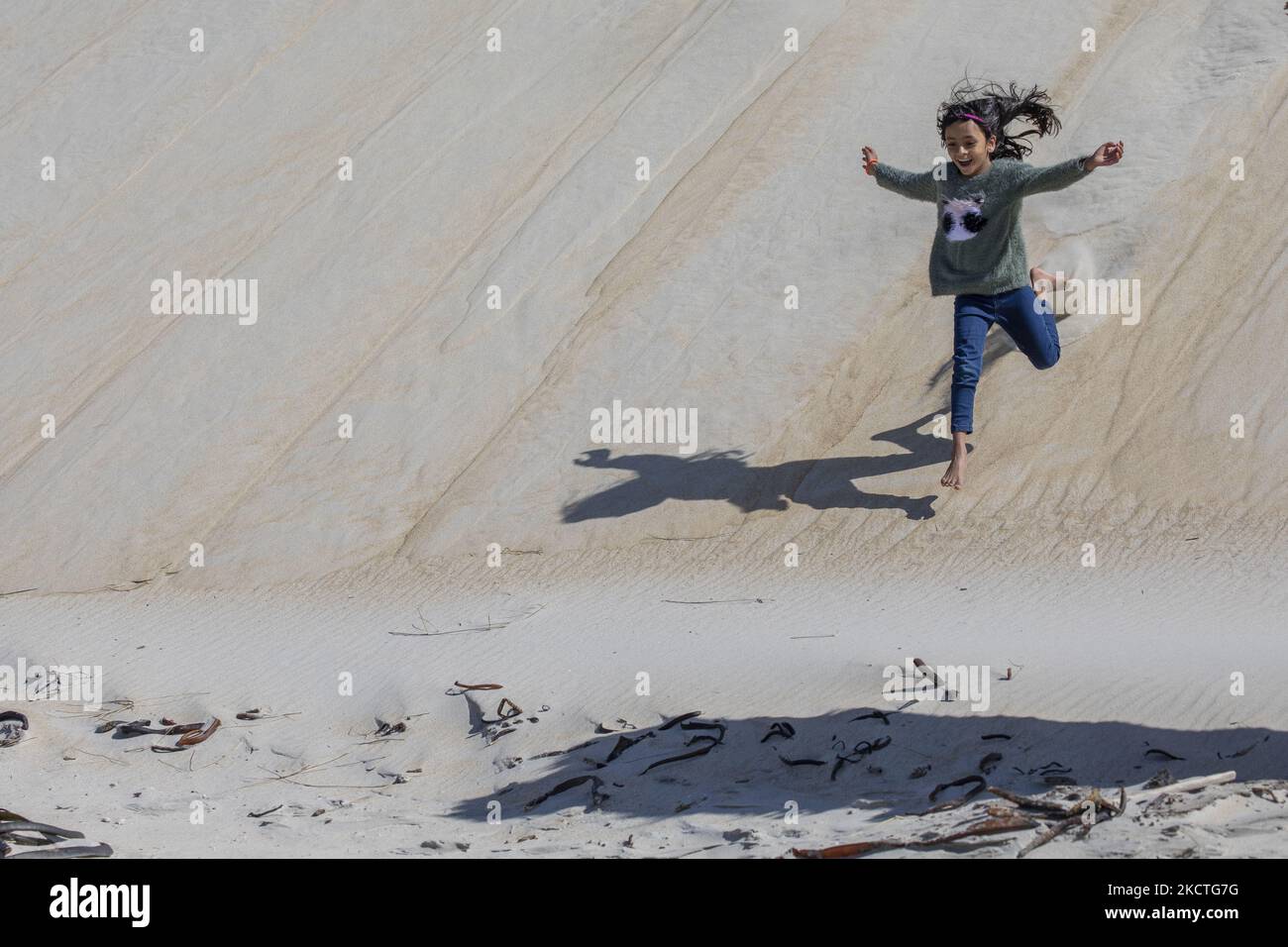 A little girl Minudi Menulya runs down a sand dune in Sandfly Bay near ...