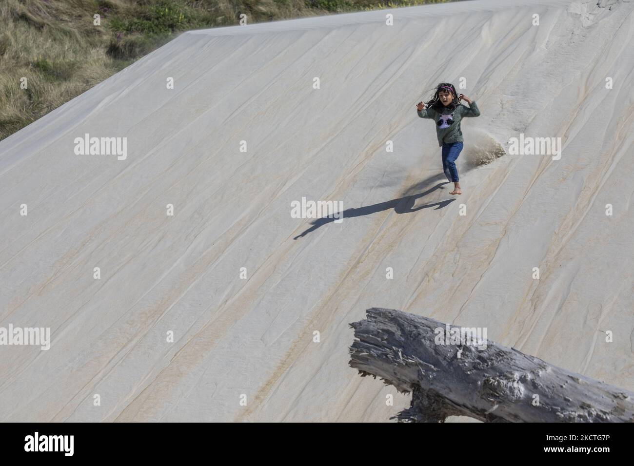A little girl Minudi Menulya runs down a sand dune in Sandfly Bay near ...