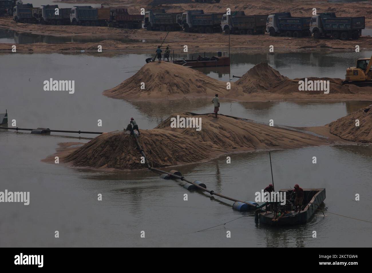 Laborers and transporting vehicles are seen inside the Kuakhai river as they are busy in the ...