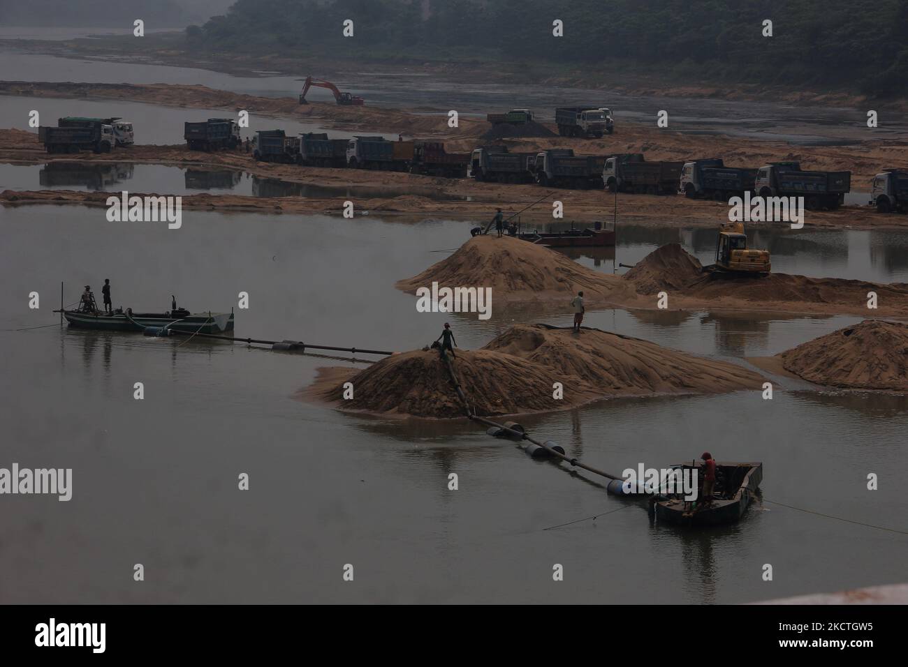Laborers and transporting vehicles are seen inside the Kuakhai river as they are busy in the ...