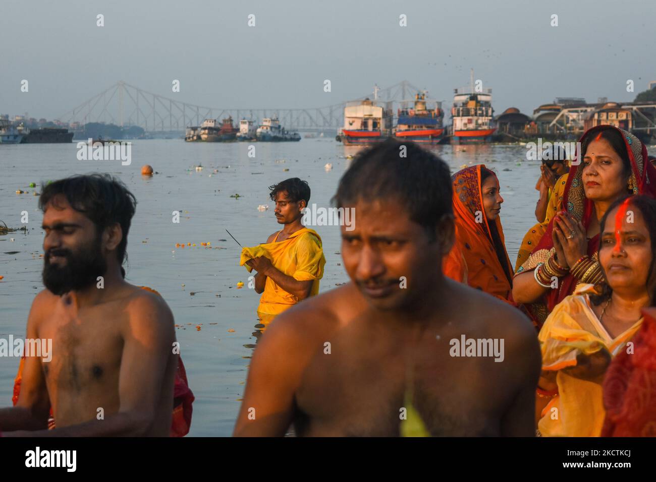 A man is seen offering prayers to Sun god , during sunset time at a riverside in Kolkata , India ...