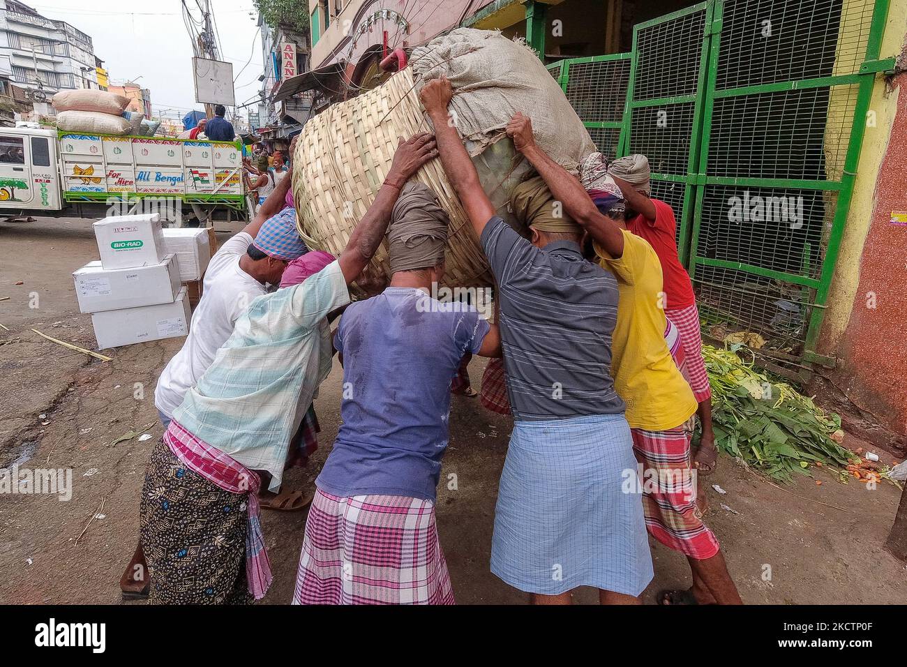 Laborers are seen lifting bags of produce , outside a farmer market in ...