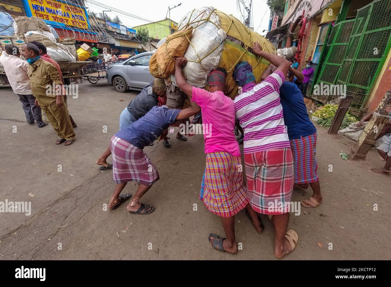 Laborers are seen lifting bags of produce , outside a farmer market in ...