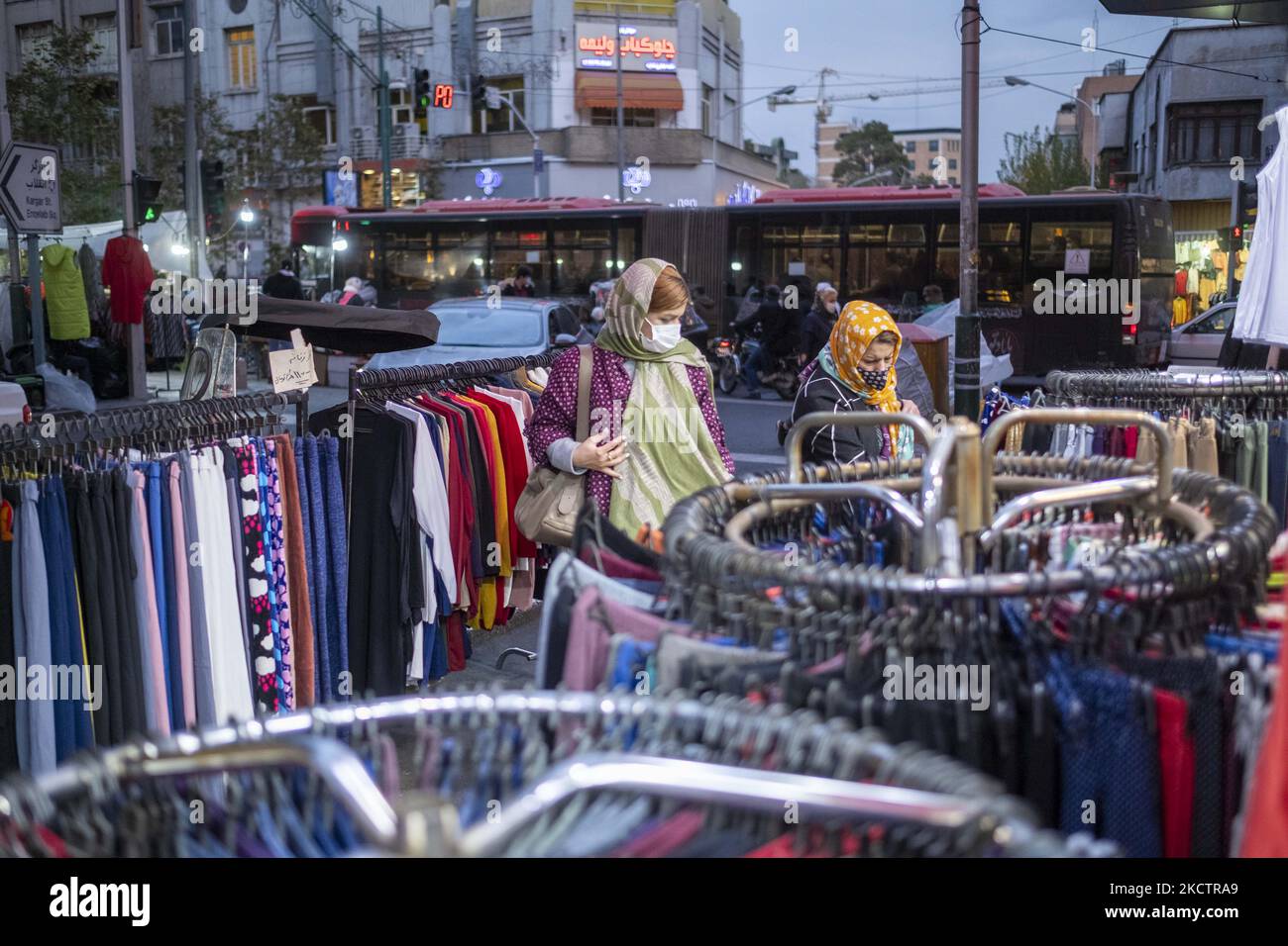 Iranian women wearing protective face masks look on clothes while ...