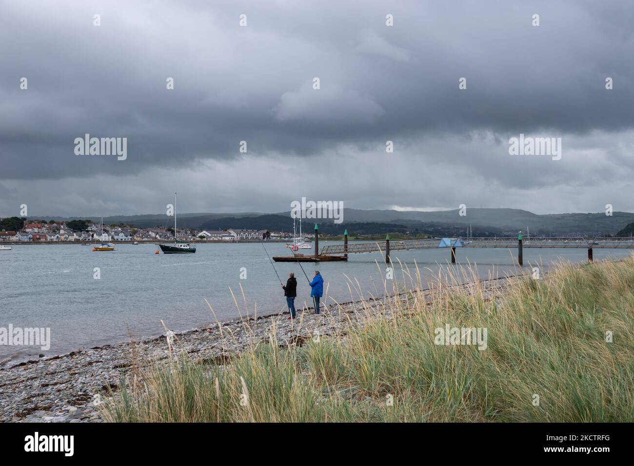Two fishermen by the river Conwy on a rainy October day in North Wales ...