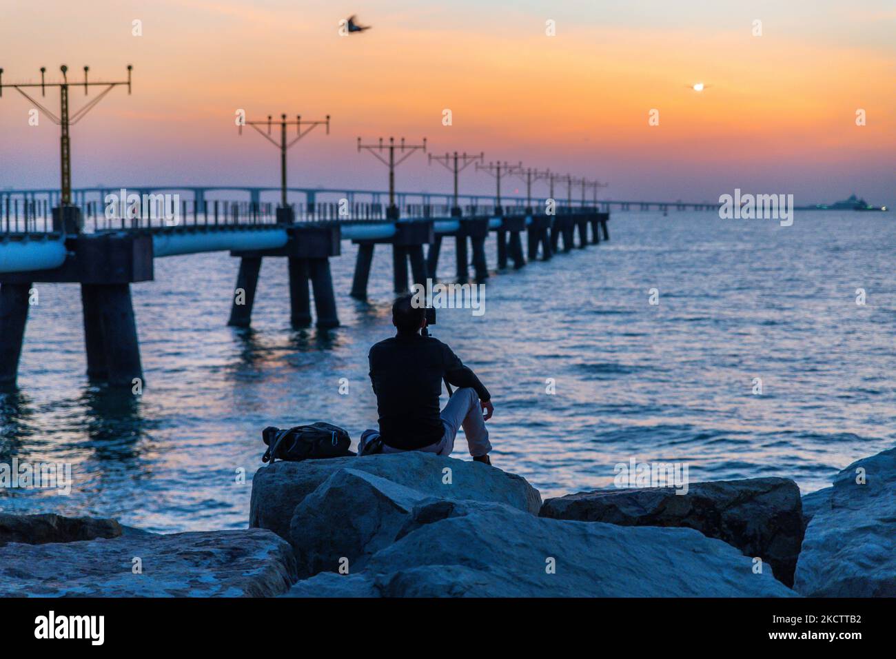 A photographer captures the landing of planes in the sunset at Hong ...