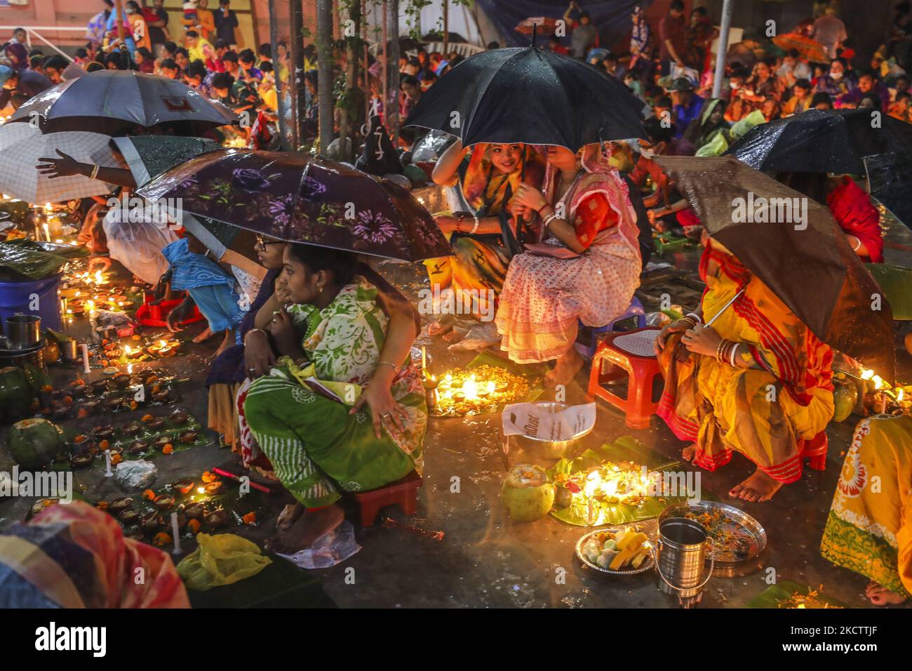 Hindu devotees sit with oil lamps and pray at the Shri Shri Lokanath ...