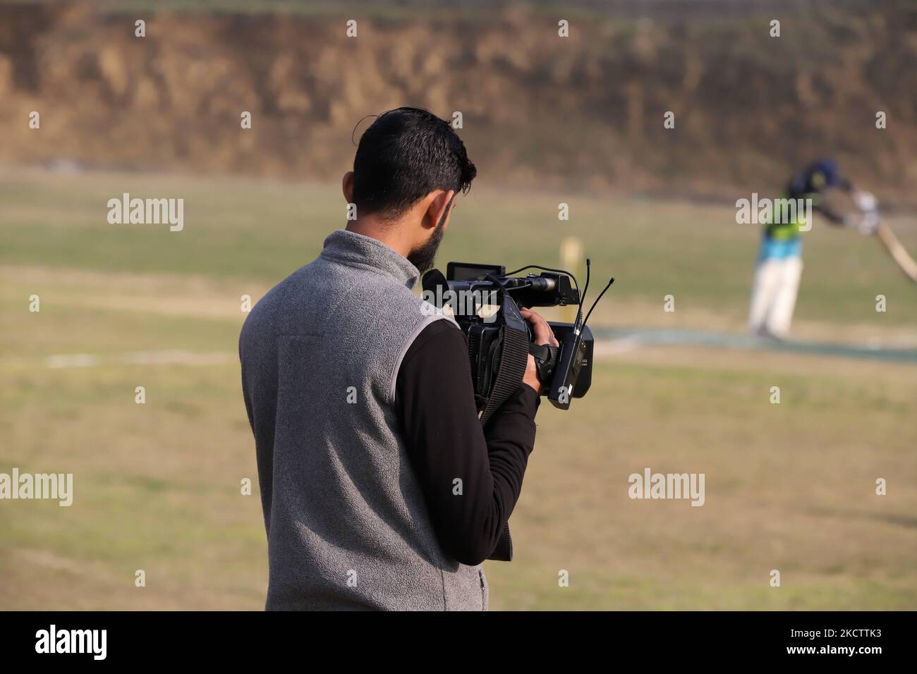 A Cameraman shoots video as Kashmiri boys play cricket during autumn ...
