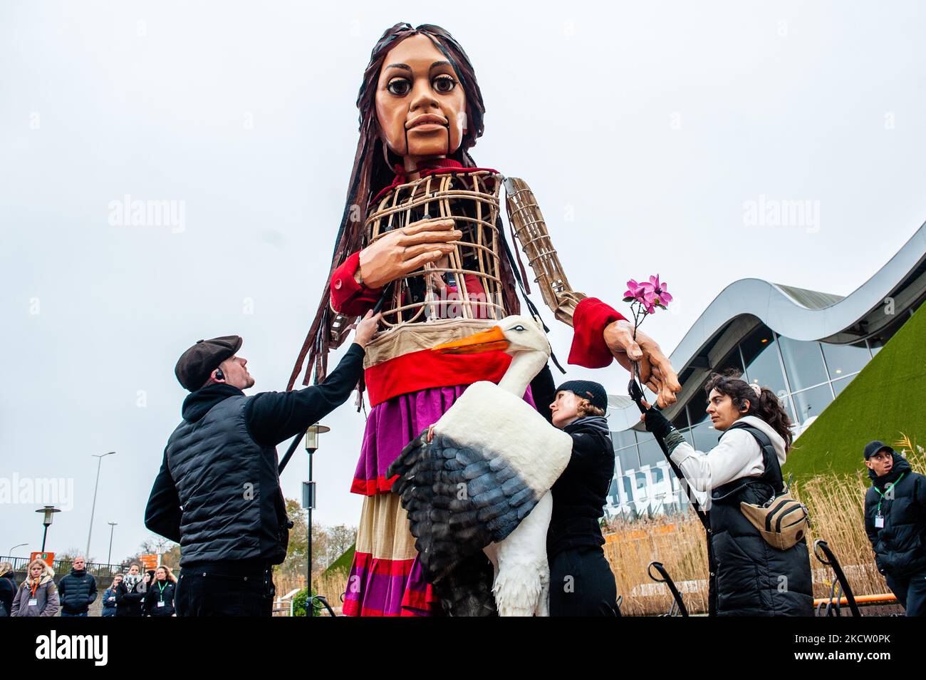A big puppet bird is giving a hug to the giant puppet 'Little Amal', a ...