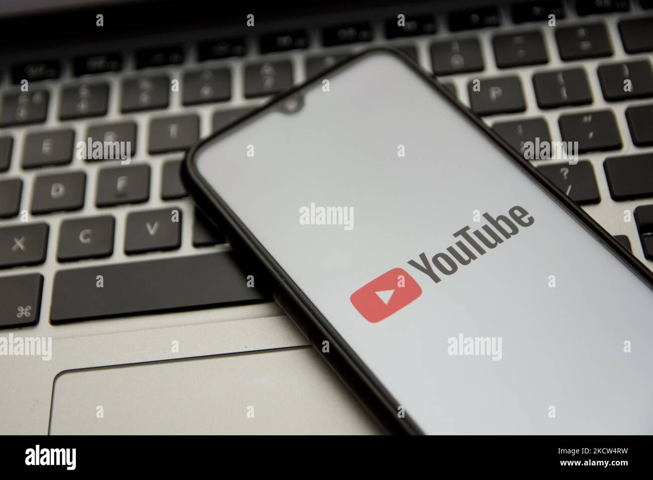 In this photo illustration an Youtube logo seen displayed on a smartphone screen with a computer ...