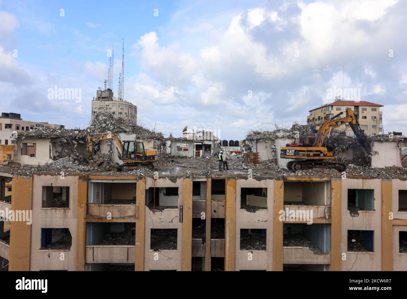 Palestinian workers clear the rubble of Al-Jawhara Tower building that ...