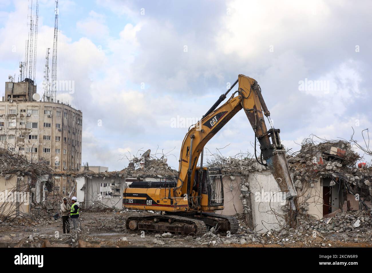 Palestinian workers clear the rubble of Al-Jawhara Tower building that ...