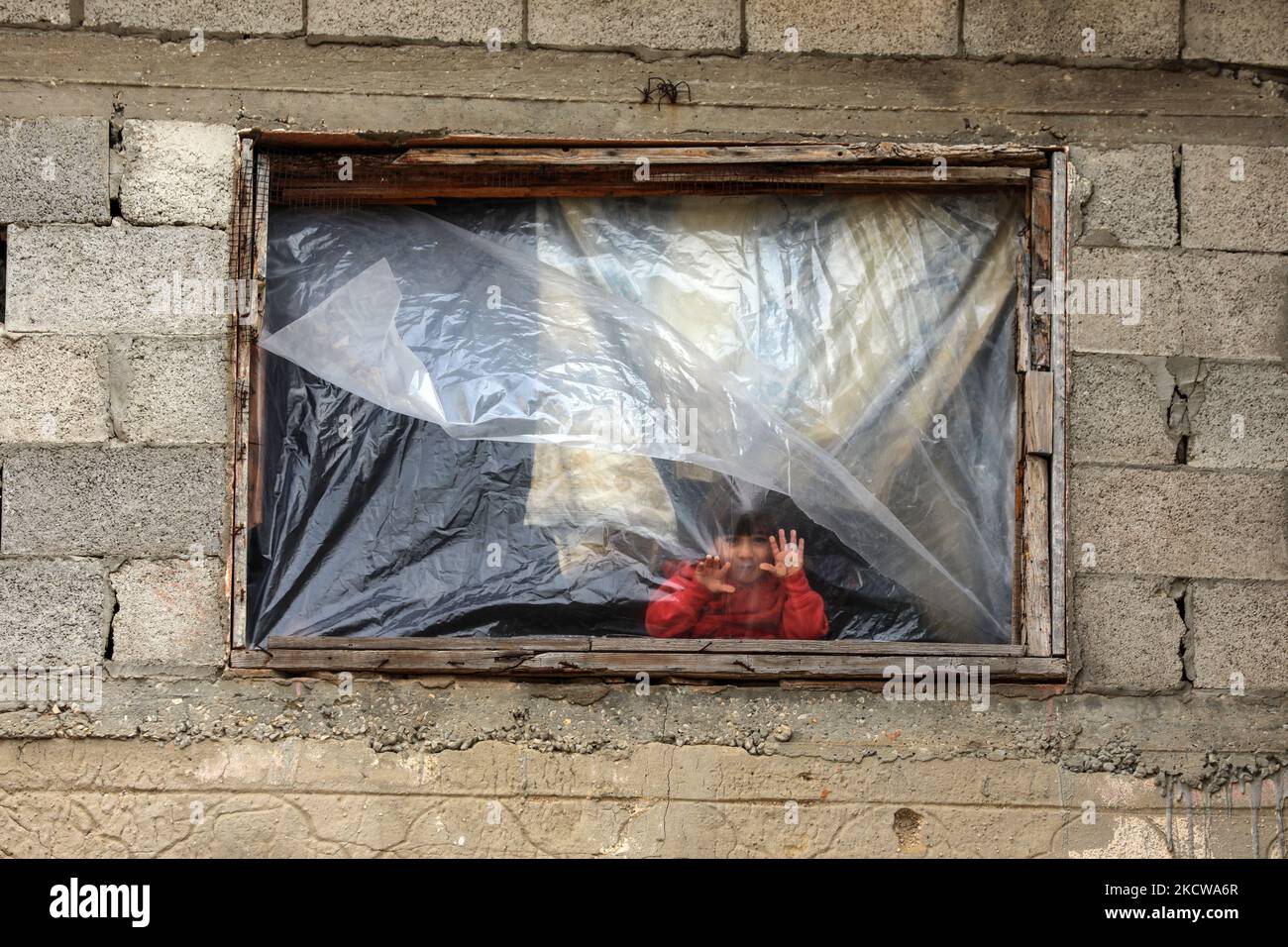 A Palestinian child looks out the window of her family's house during ...