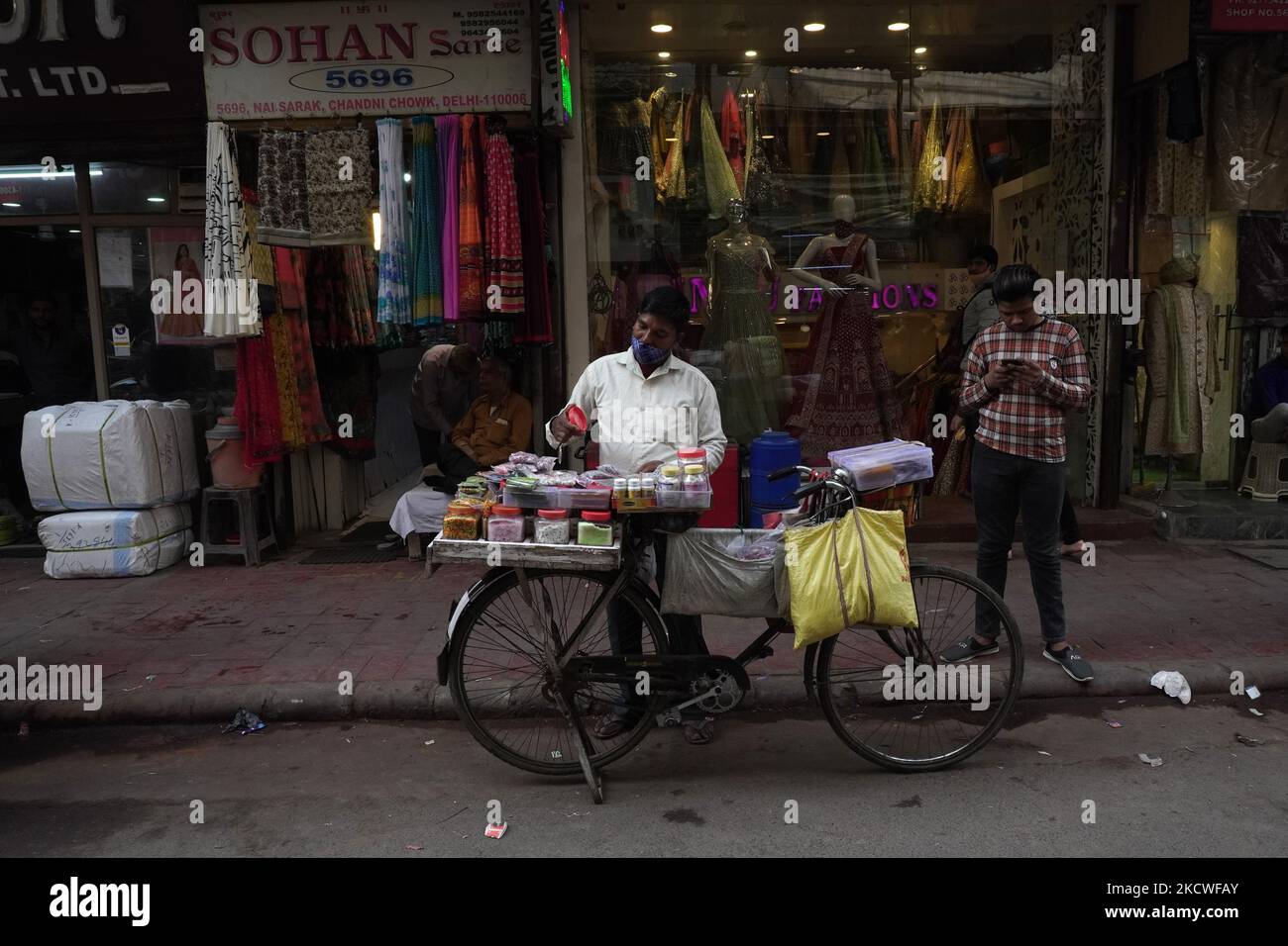 A street vendor adjusts his items on a cycle as he waits for customers ...