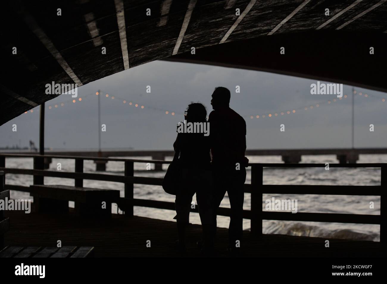 A couple seen walking under the bridge near the beach in Progreso. On ...