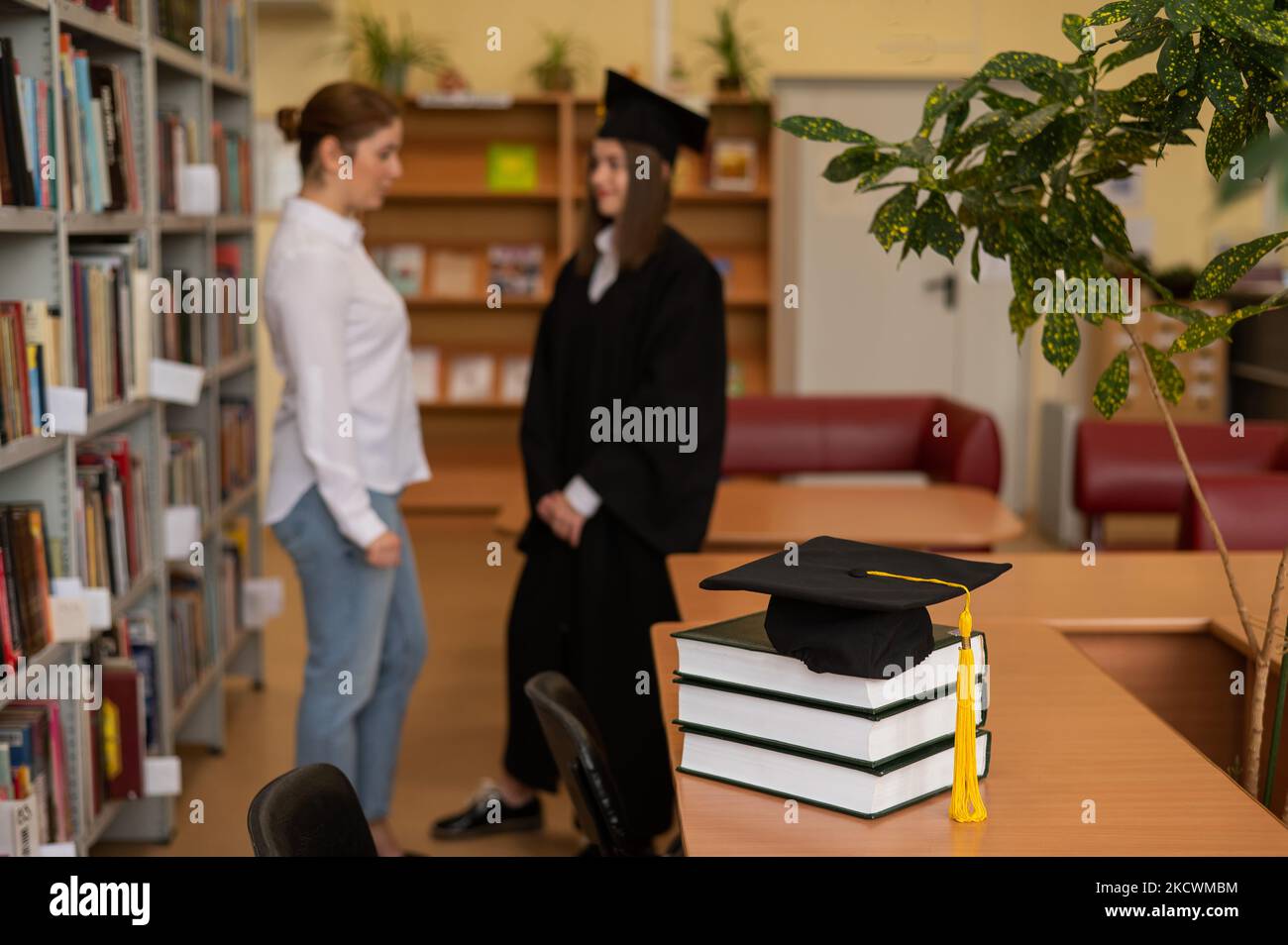 Close-up of a graduation cap on a stack of books in a library. teacher ...