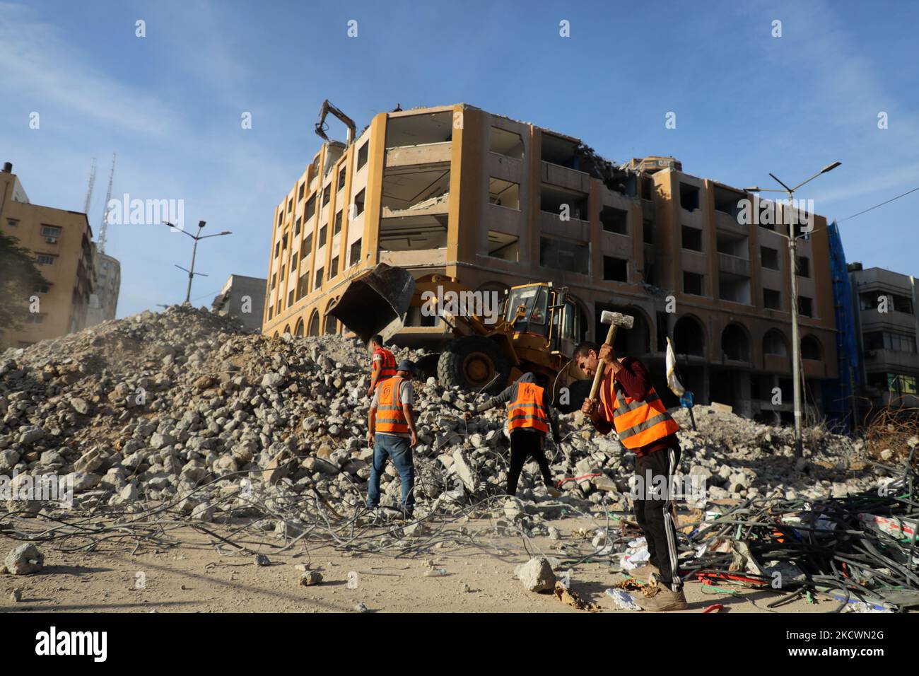 Palestinian workers clear the rubble of al-Jawhara Tower in Gaza City's ...