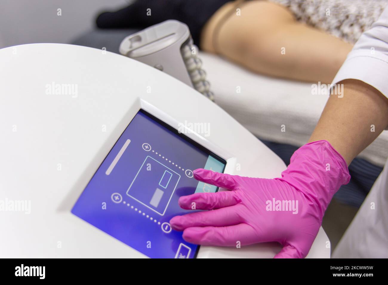 A medic adjusts the operating mode of the anti-cellulite massage ...