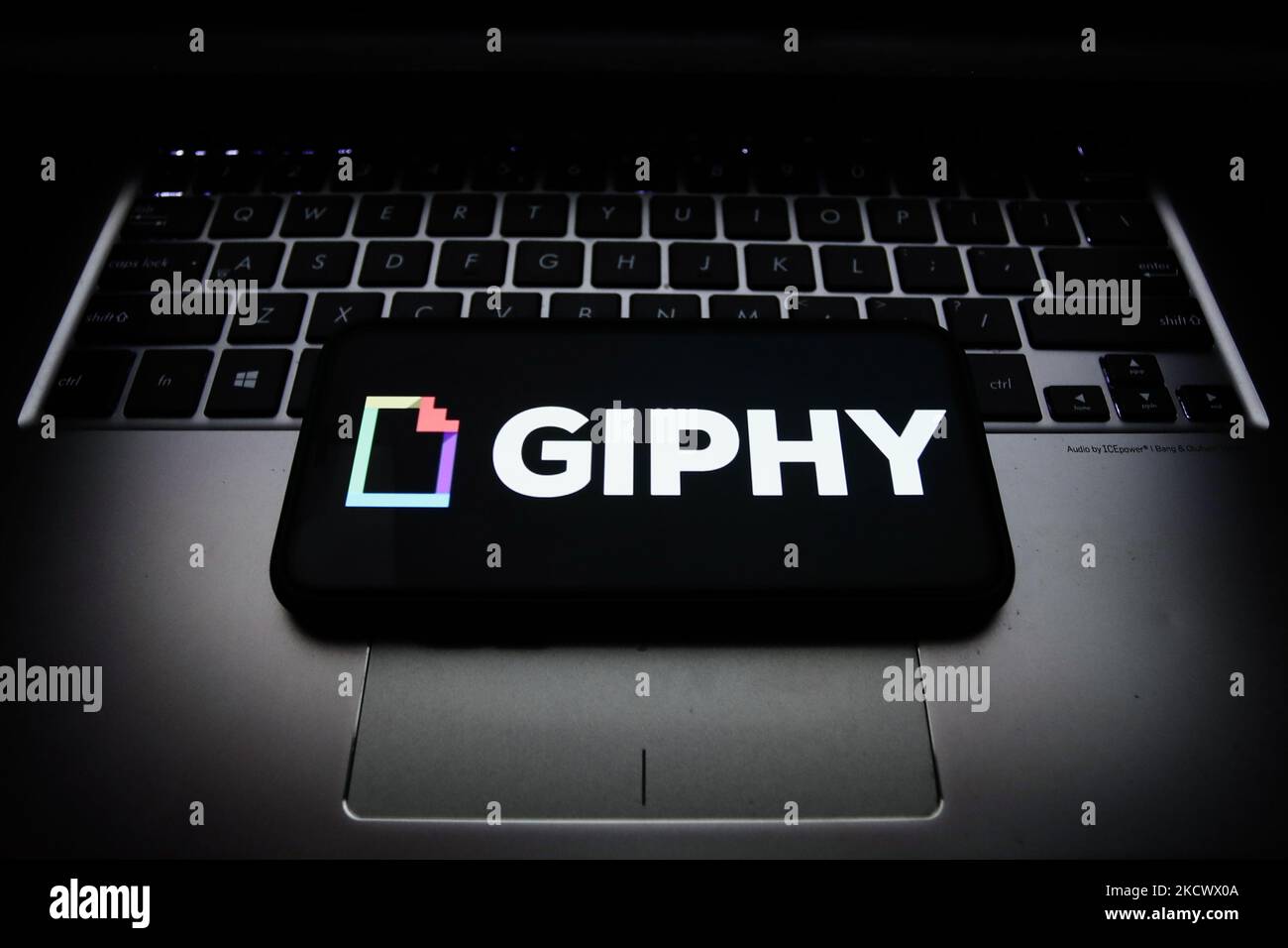 Giphy logo displayed on a phone screen and a laptop keyboard are seen ...