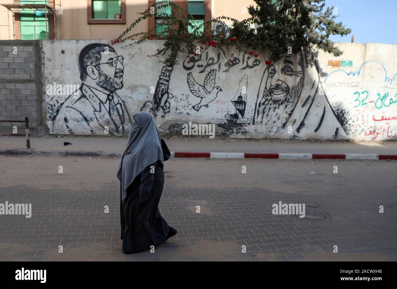 A Palestinian woman walks past graffitis of Hamas late leaders Sheikh ...