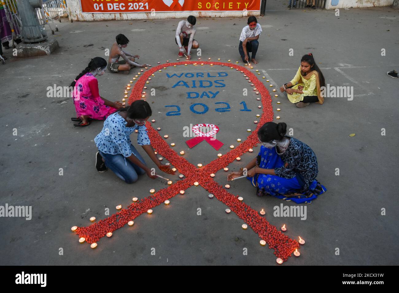 Activist are seen lighting lamps at the boundary of a large red ribbon ...