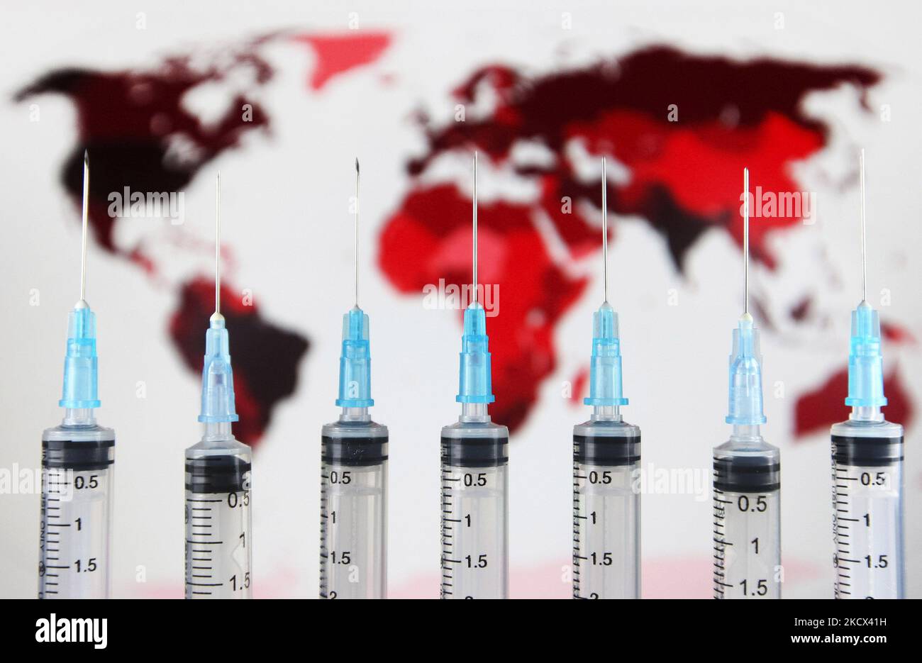 Syringes and a coronavirus COVID-19 spread map are pictured in this ...