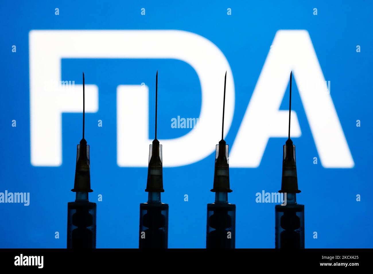 Medical syringes and FDA logo displayed in the background are seen in ...