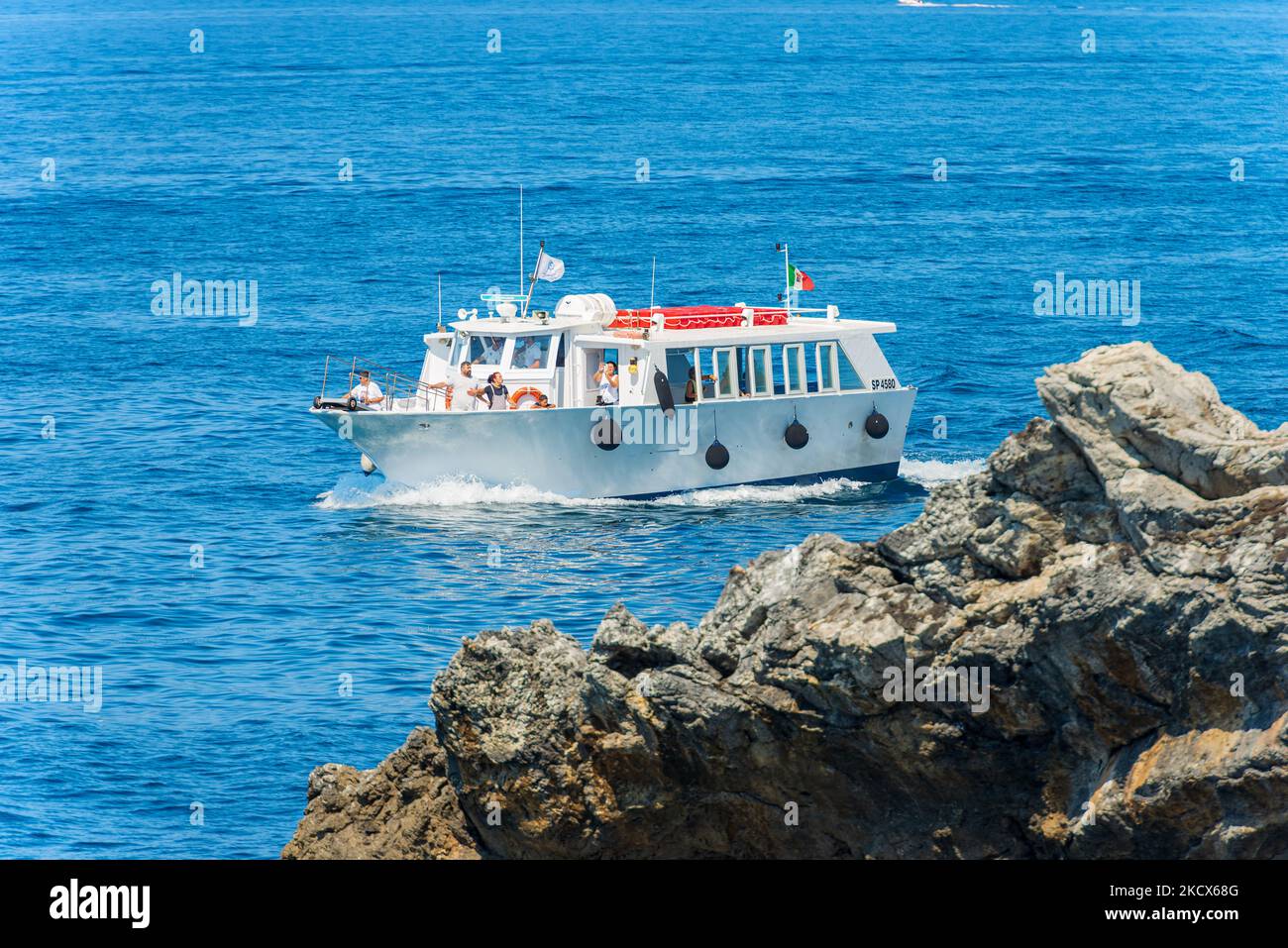 White ferry with tourists on board is arriving in the small port of ...