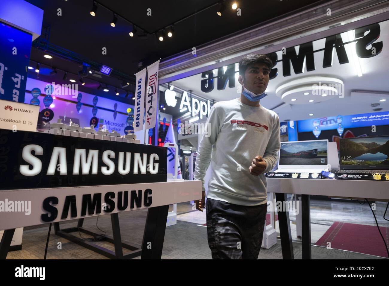 An Iranian salesman walks past the logos of the Samsung South Korean ...