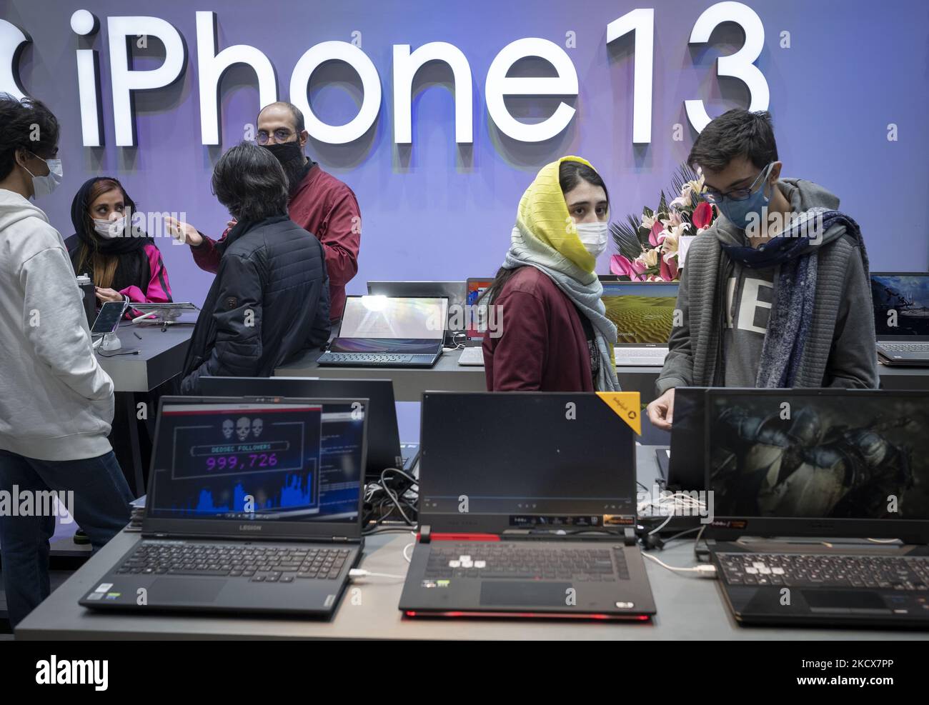 An Iranian man and a woman stand behind laptops in front of a logo of ...