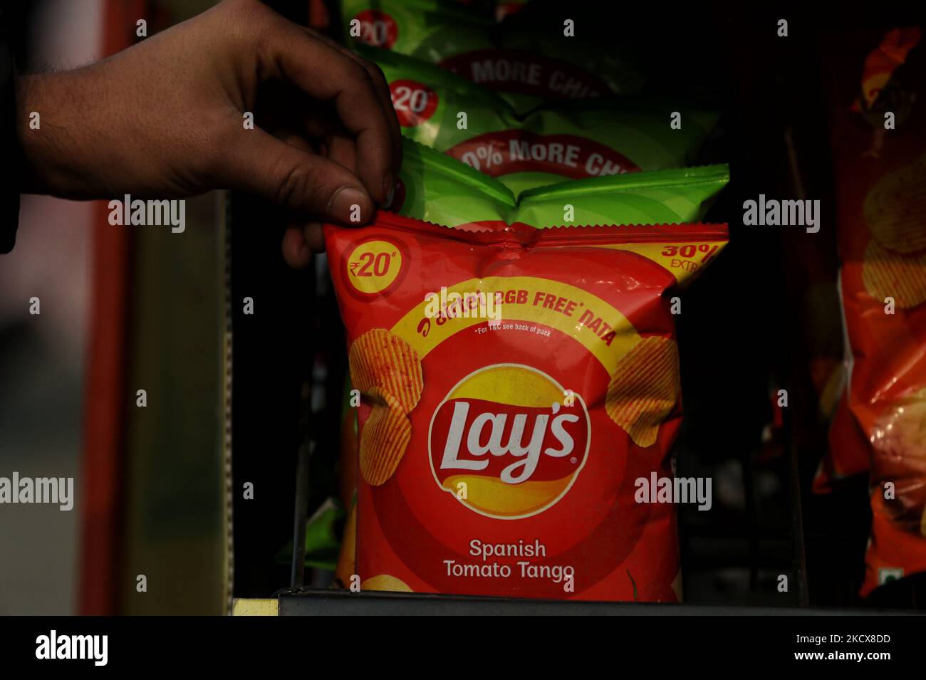 A man picks a pack of PepsiCo Lays Potato chips from a shop in ...