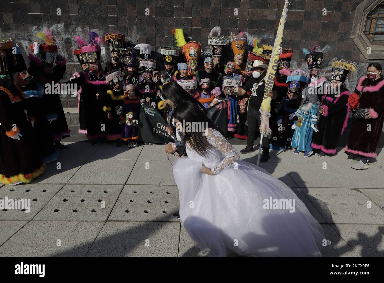 Two women in white dresses run in front of a group of chinelos as they ...