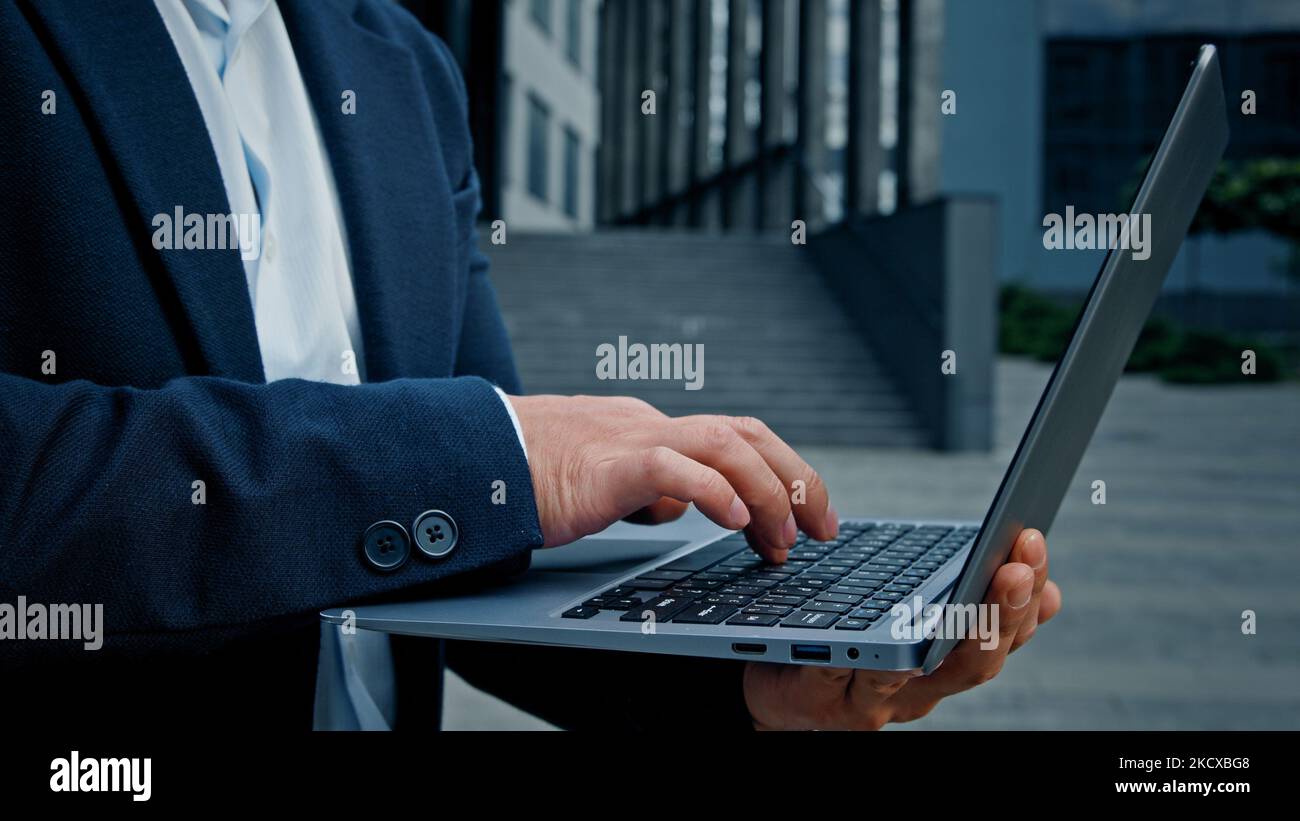 Close up male hands unrecognizable businessman typing laptop outdoors ...