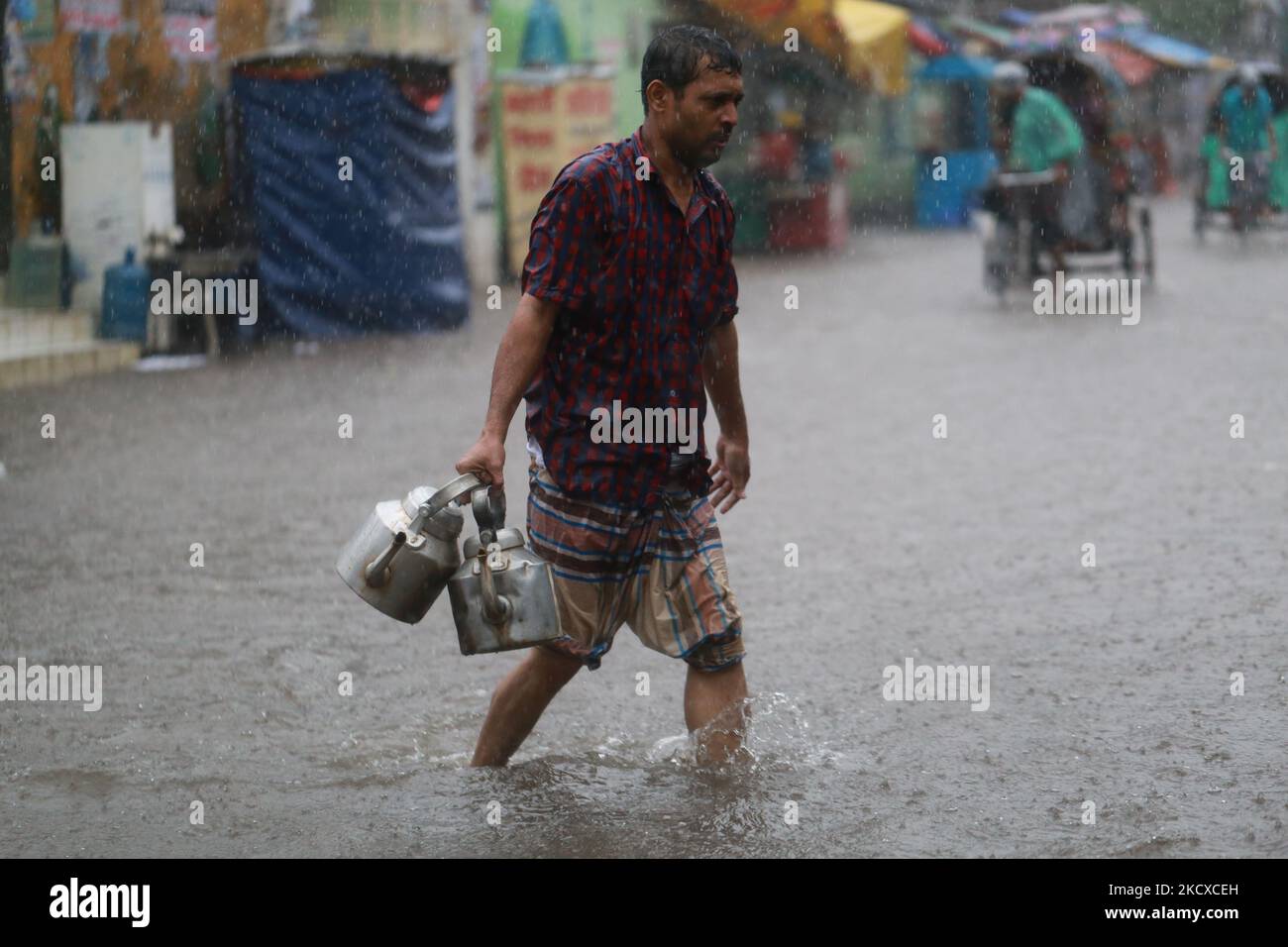 A man walks through water during rainfall due to cyclone Jawad in Dhaka ...