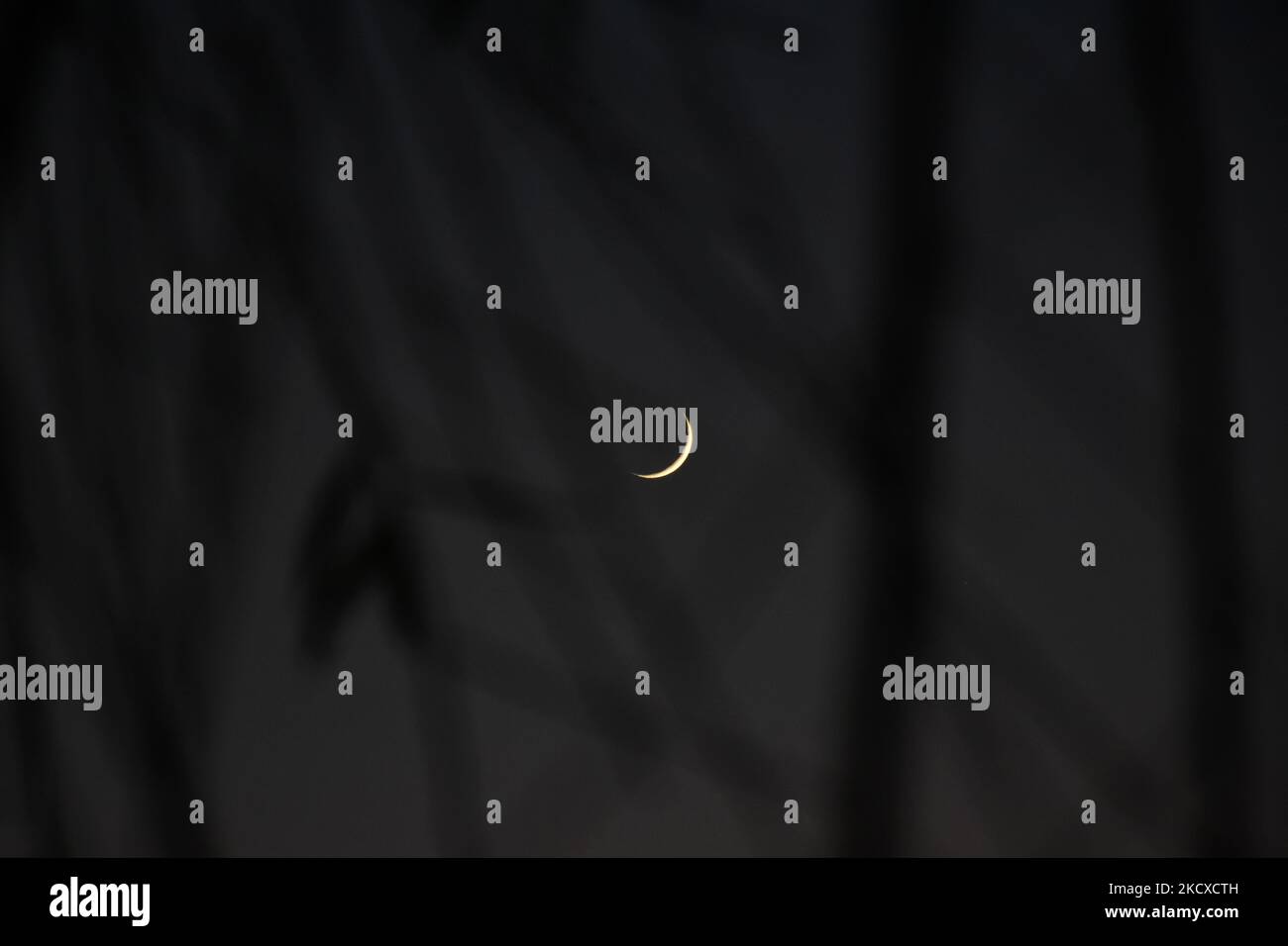 A crescent moon rises over Dal Lake on a cold winter evening in ...