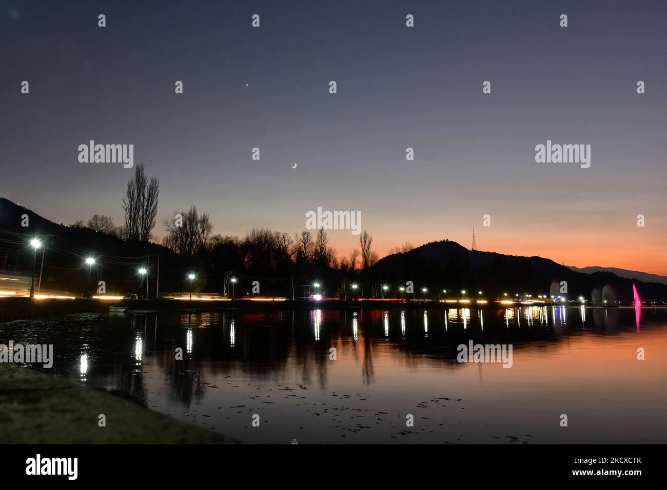 A crescent moon rises over Dal Lake on a cold winter evening in ...