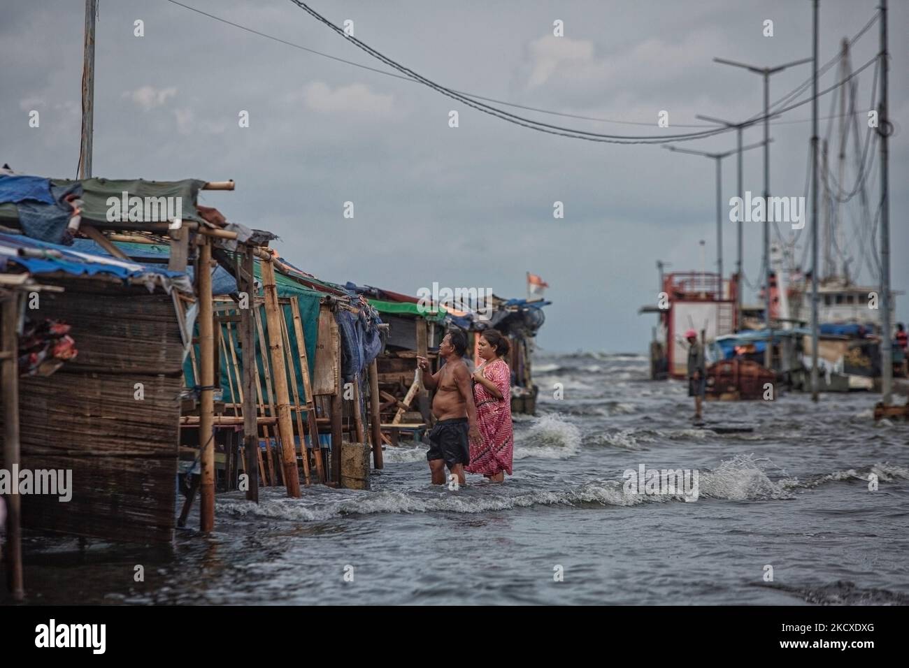 Residents passes by a food stall damaged by tidal waves in Jakarta's ...