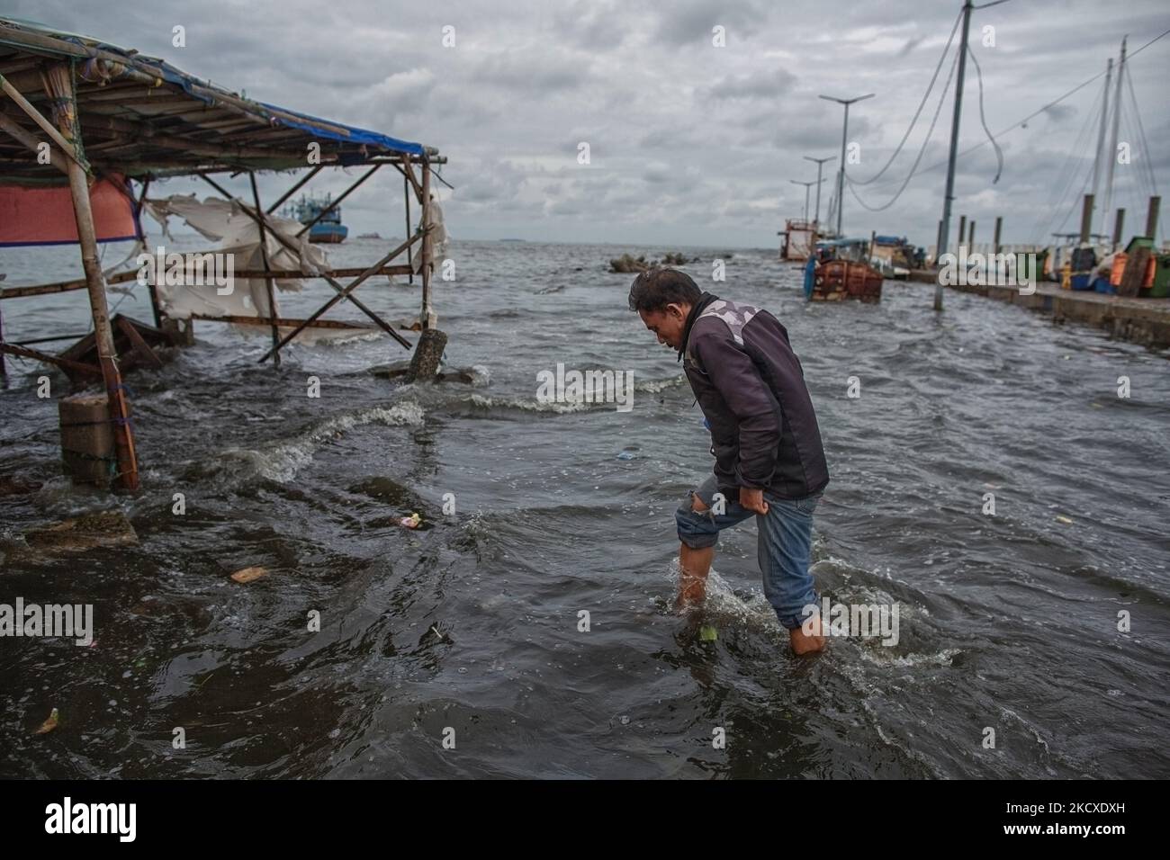 A man passes by a food stall damaged by tidal waves in Jakarta's ...