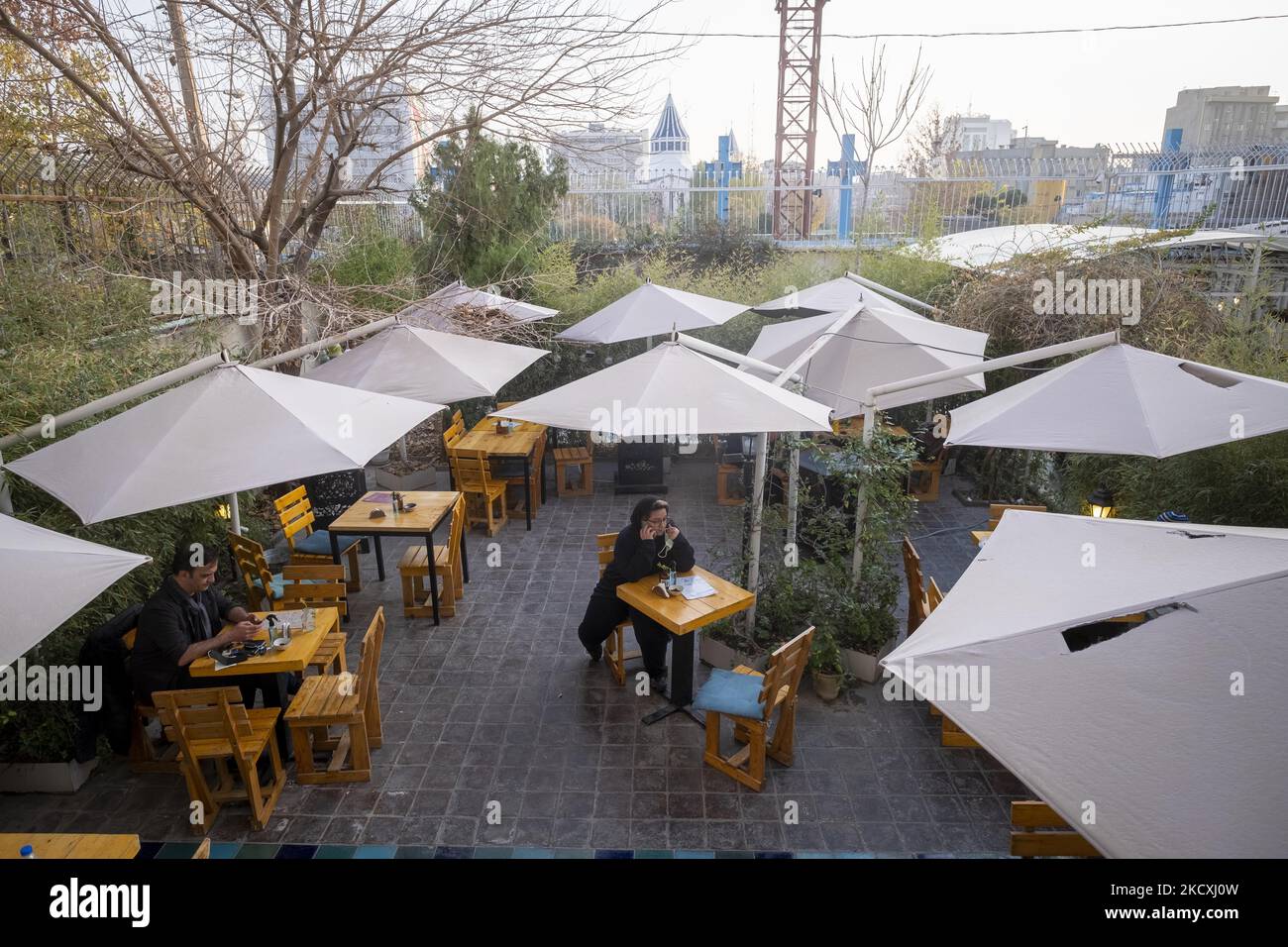 An Iranian cafe-woman speaks on her smartphone while sitting in a cafe ...