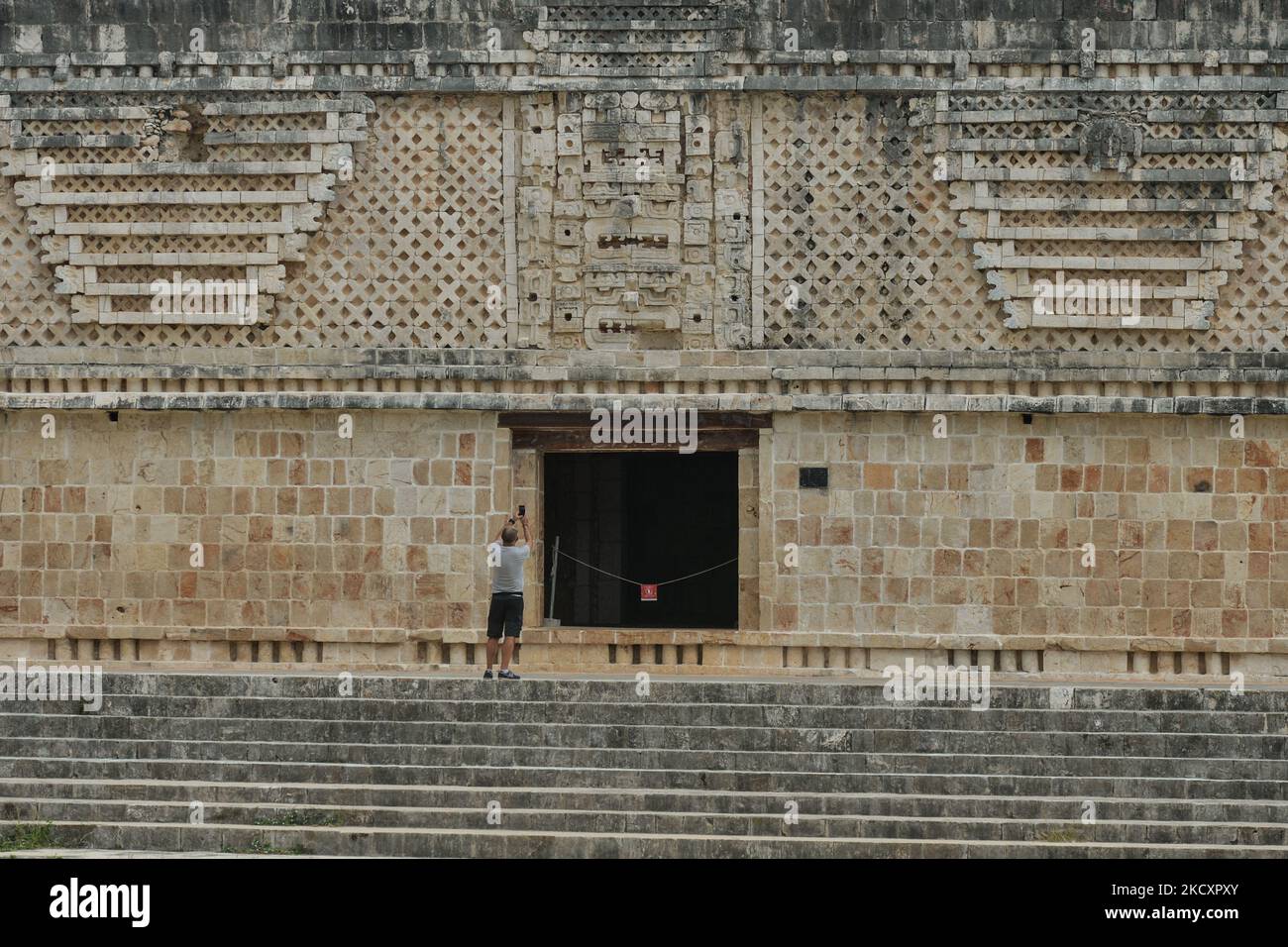 A tourist takes pictures of the Maya symboles and images of people and ...