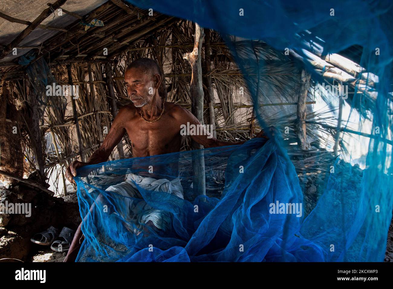 Raghuram prepares his fishing net in a makeshift shelter before going ...