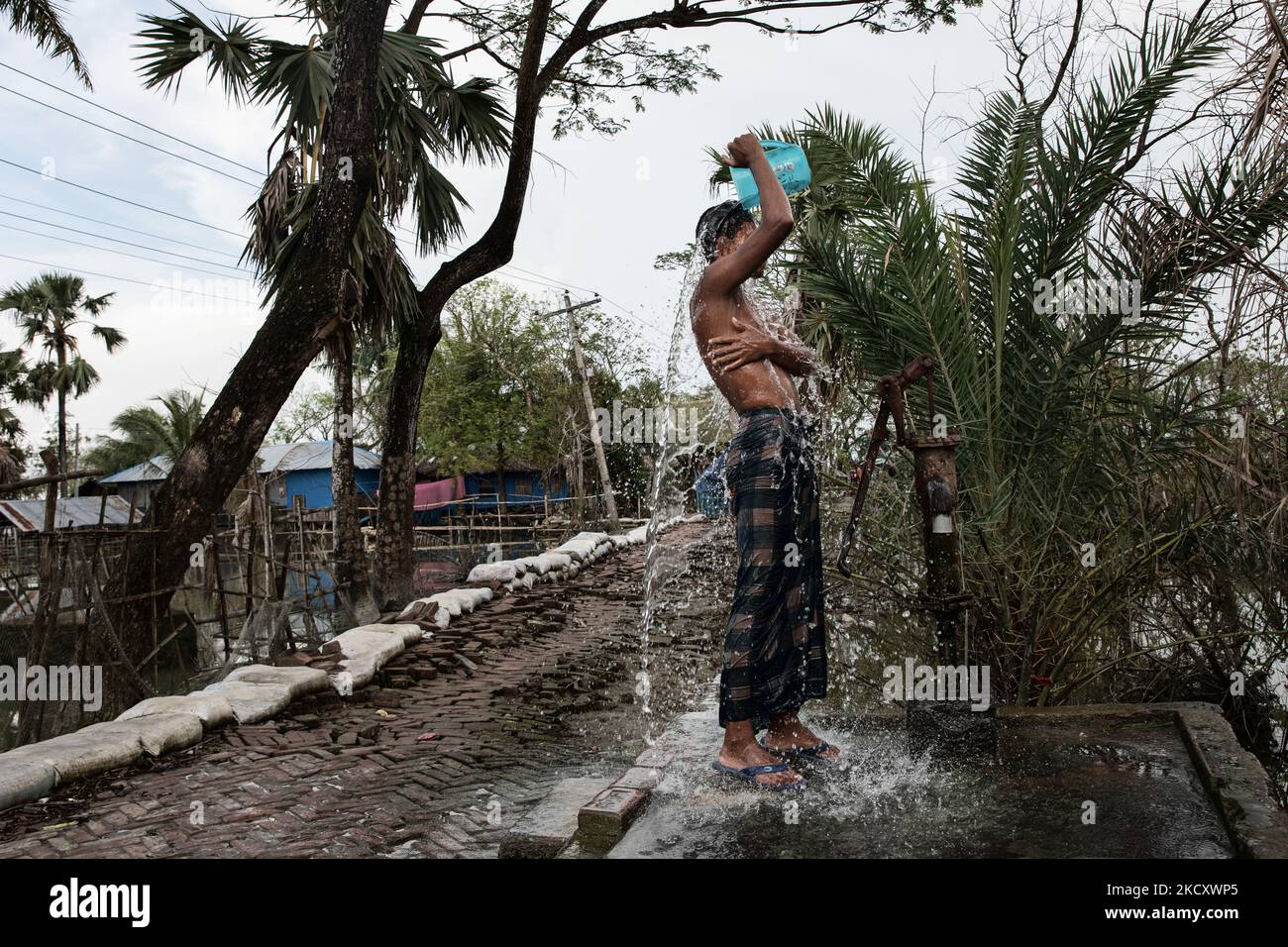 A man takes bath on the roadside tubewell after his house was aftected by the cyclone amphan ...
