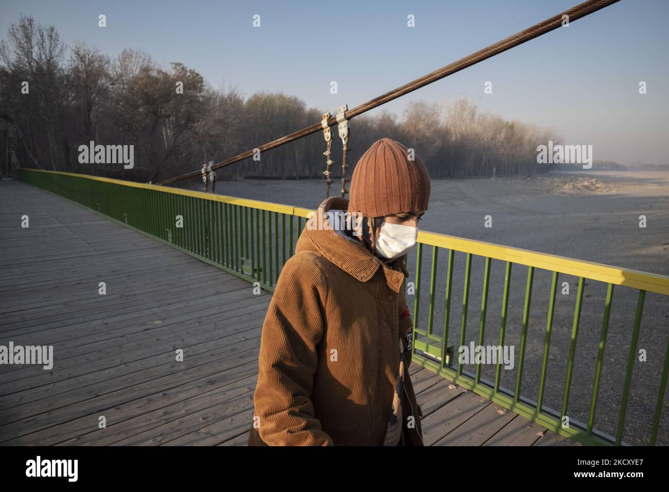 An Iranian woman walks along a bridge to cross the dried-up Zayandeh ...