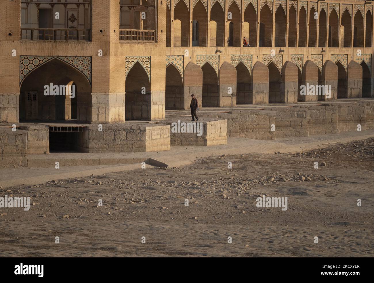 An Iranian man walks on a foundation of the Khaju historical bridge on ...