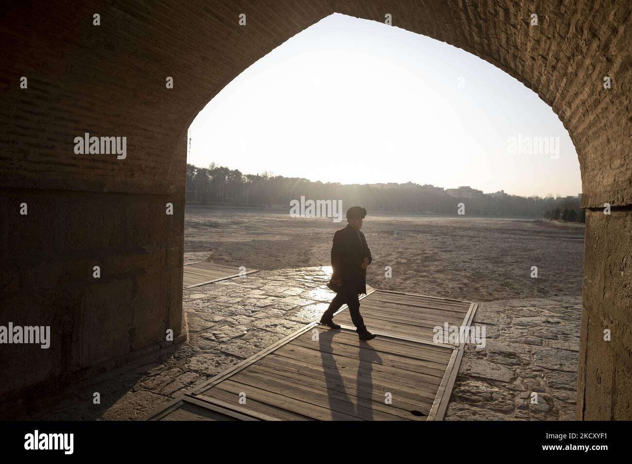 An Iranian man walks along the Khaju historical bridge on the dried-up ...