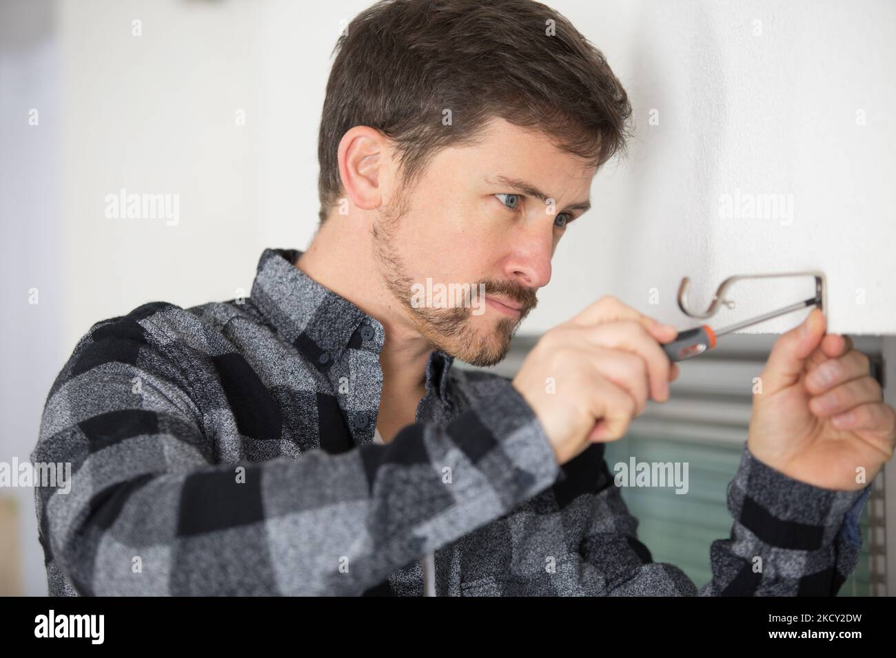 man preparing to screw a hook to the wall Stock Photo - Alamy