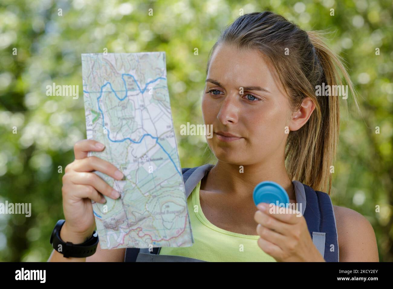 female hiker checking the map while holding her compass Stock Photo - Alamy