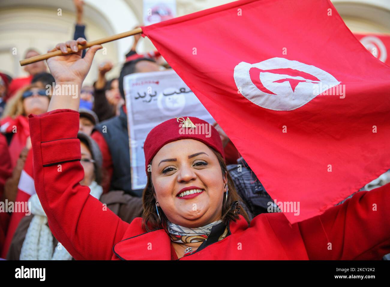 A smiling female supporter raises the Tunisian flag during a ...