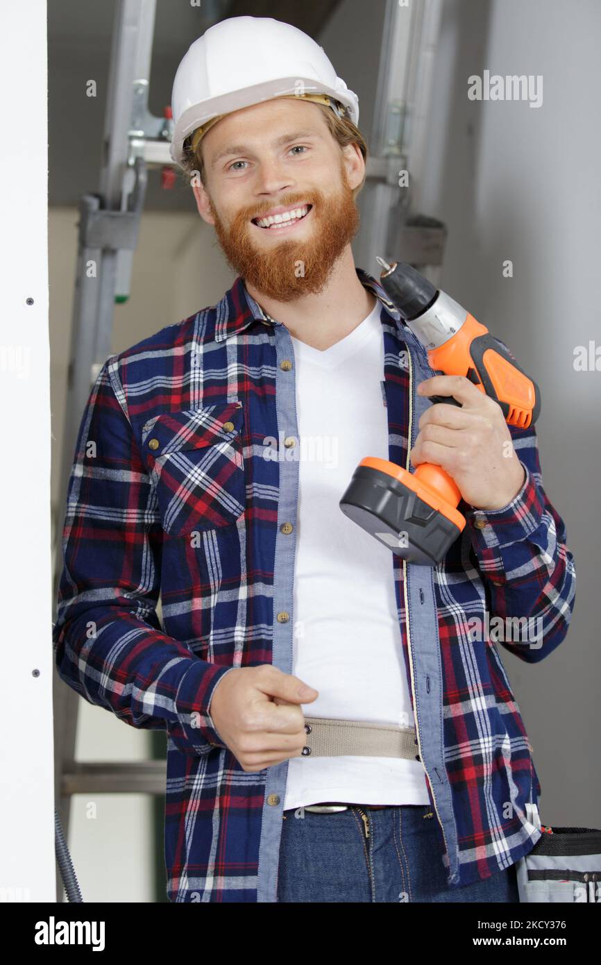 portrait of young handyman using electric drill Stock Photo - Alamy